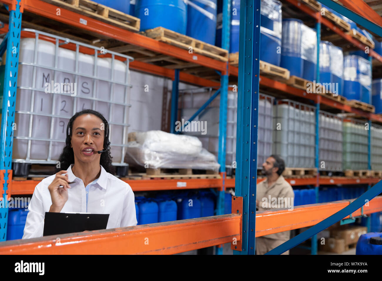Female manager talking on headset while holding clipboard Stock Photo ...