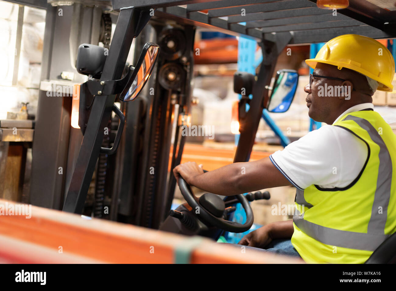 Male staff driving forklift in warehouse Stock Photo - Alamy