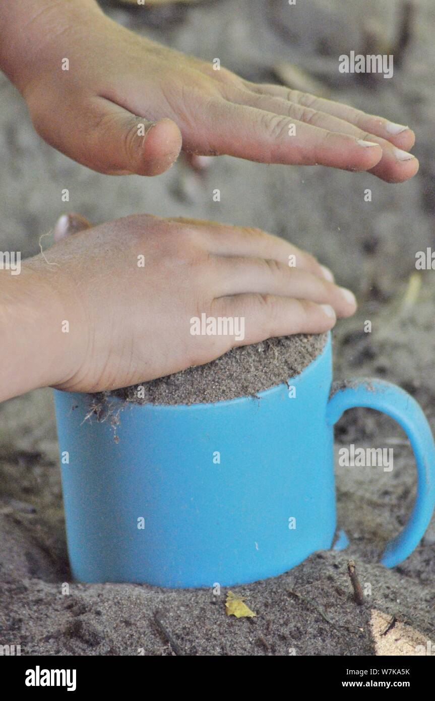 Sand, mug, child's play in the sand. Hands of the child Stock Photo - Alamy