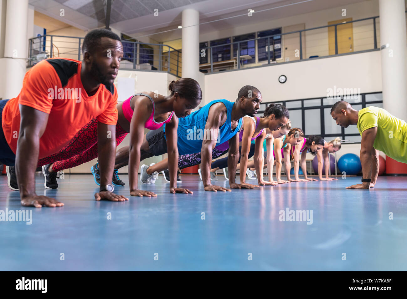 Male trainer training people to perform exercise in fitness center ...