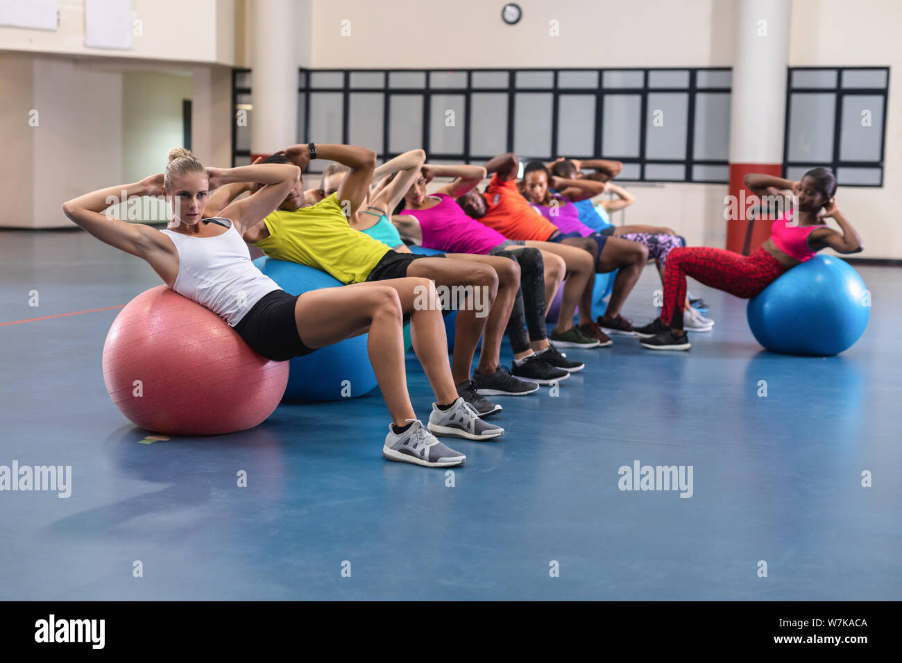 Female trainer training people to perform yoga on exercise ball Stock ...