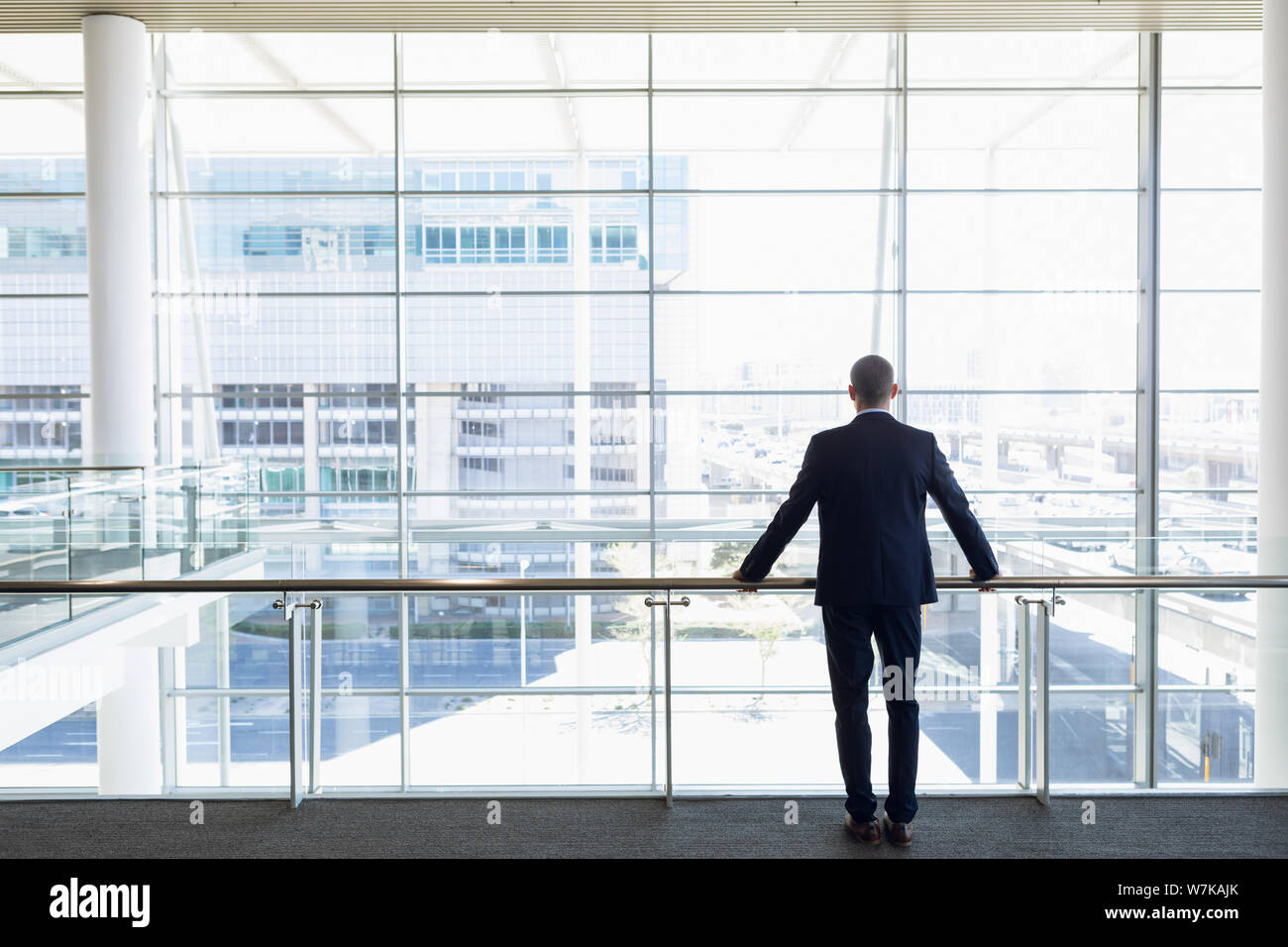 Back view of businessman looking out of office window Stock Photo - Alamy