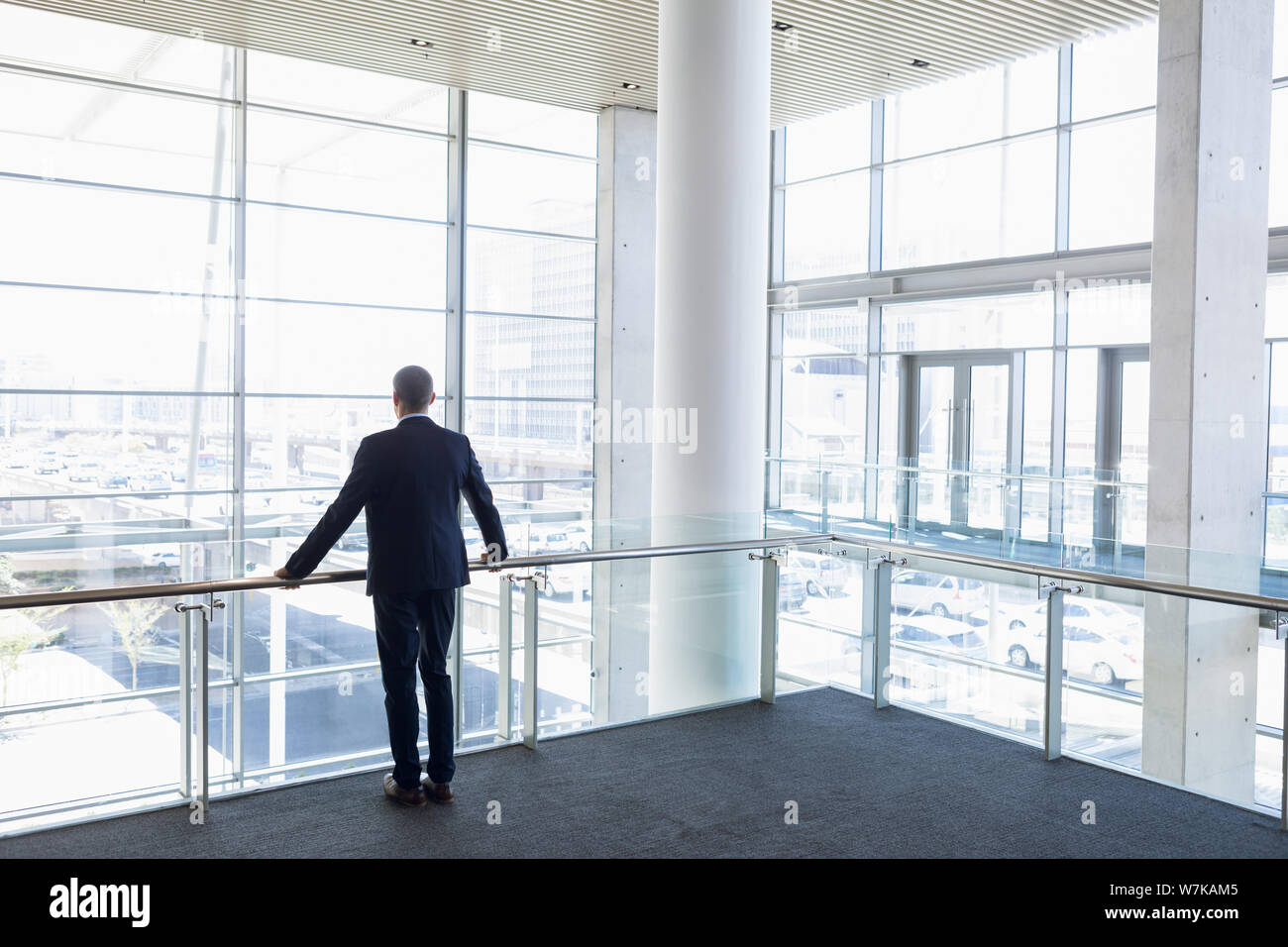 Back view of businessman looking out of office window Stock Photo - Alamy