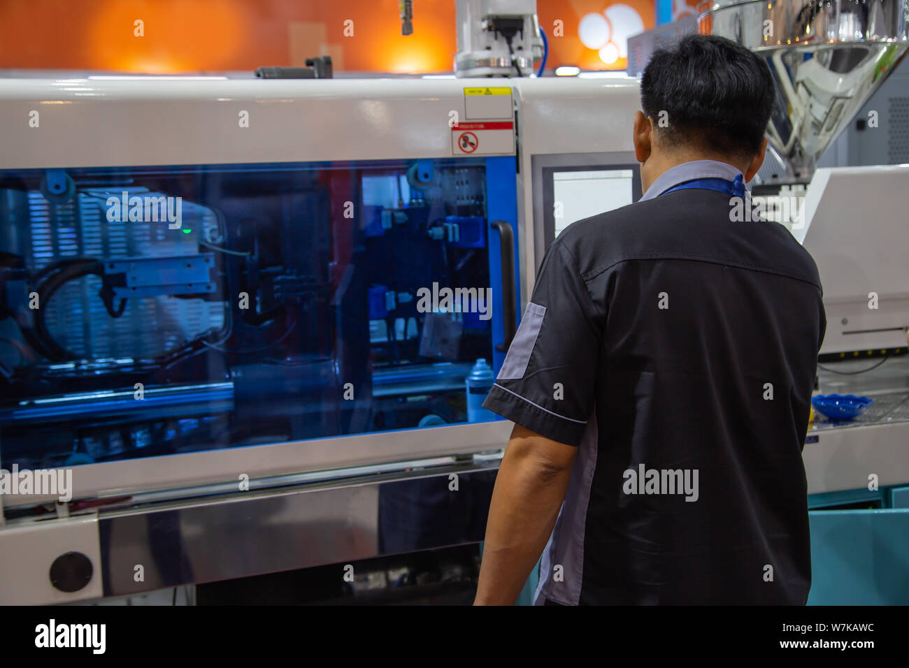 worker operating industrial plastic injection molding press machine for ...