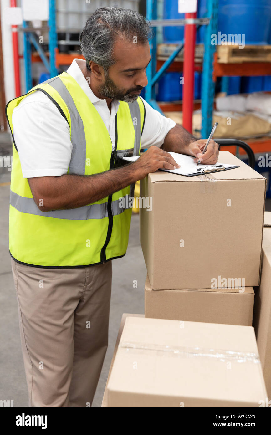 Male worker writing on clipboard in warehouse Stock Photo - Alamy