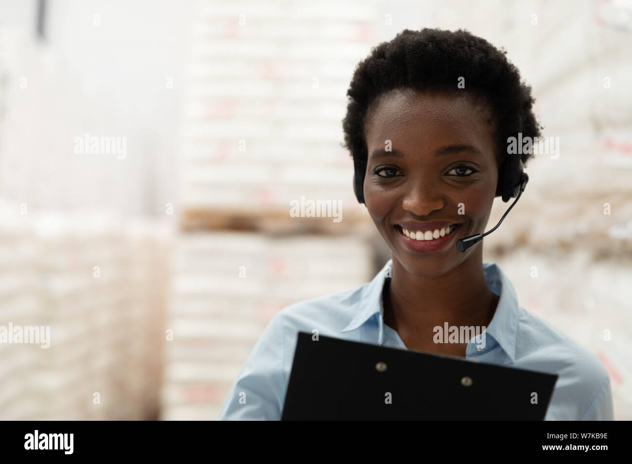 Female manager with headset and clipboard looking at camera in ...