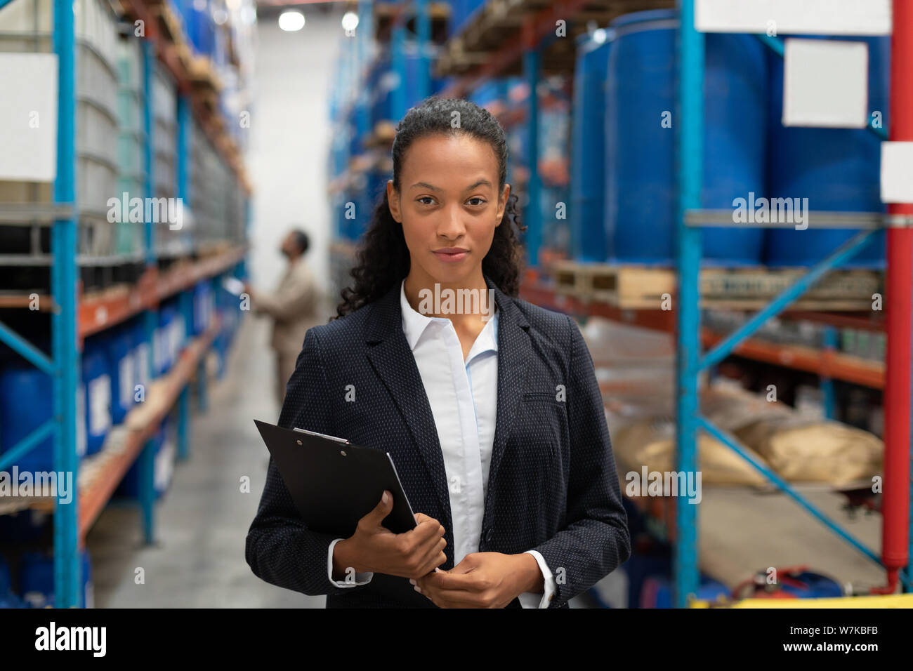 Female manager standing with clipboard in warehouse Stock Photo - Alamy