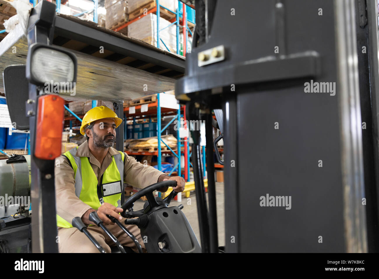 Male staff driving forklift in warehouse Stock Photo - Alamy