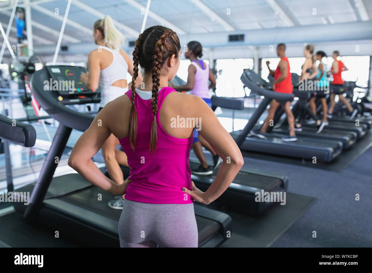 Female trainer standing with hands on hip in fitness center Stock Photo ...