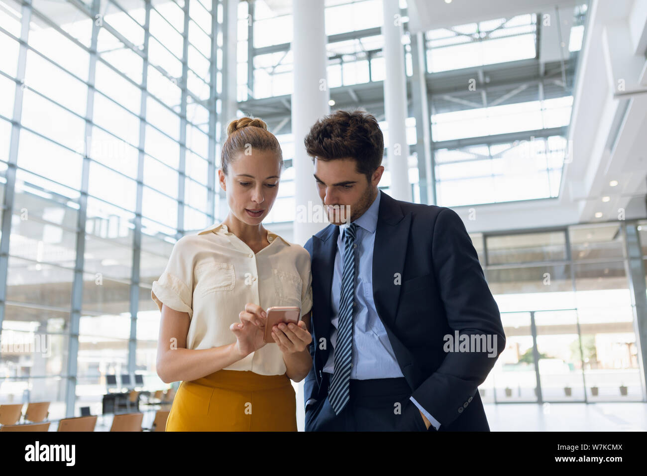 Two business people looking at phone in modern office foyer Stock Photo ...