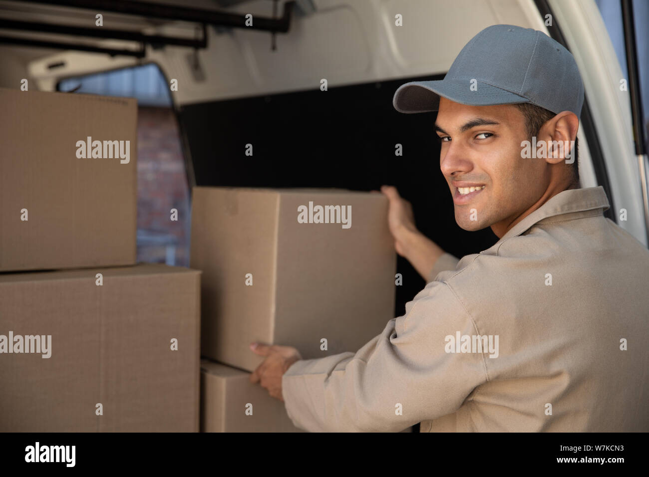 Delivery man unloading cardboard boxes from a van outside the warehouse ...