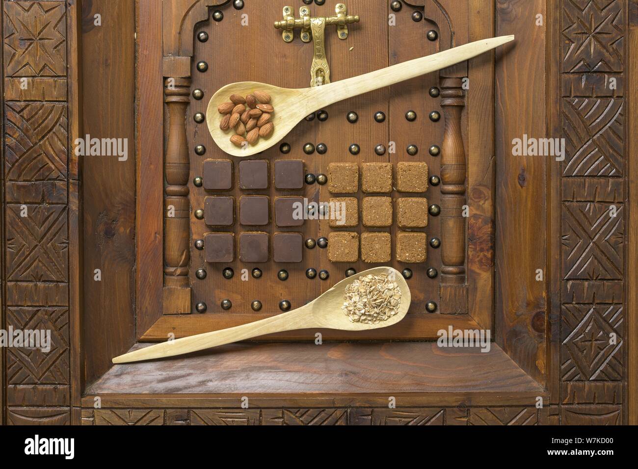 Overhead shot of square-shaped sweets with nuts in wooden spoons on ...