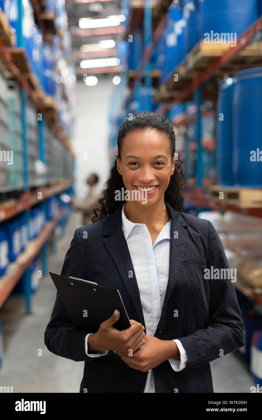 Female manager standing with clipboard in warehouse Stock Photo - Alamy