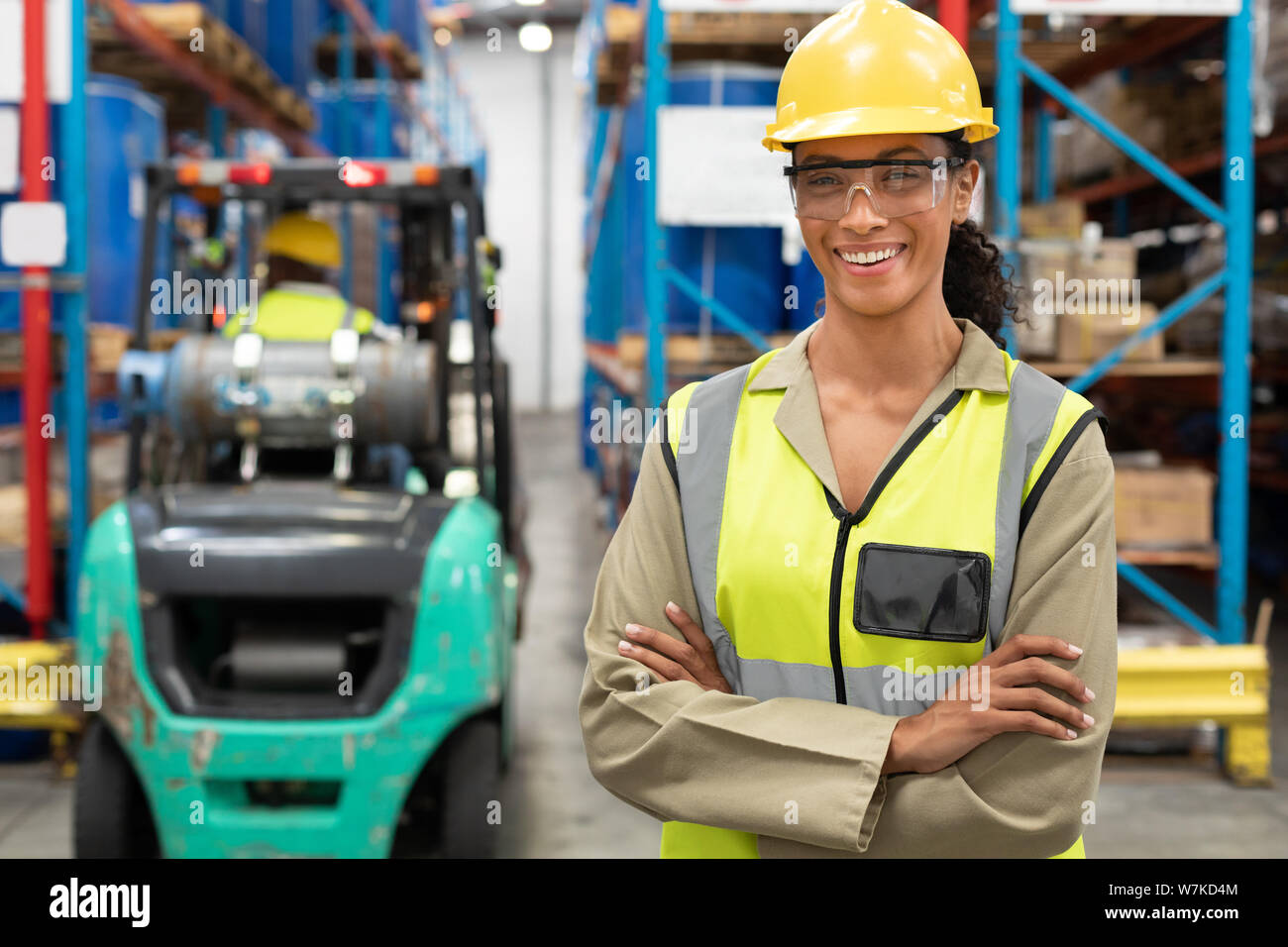 Female staff standing with arms crossed in warehouse Stock Photo - Alamy