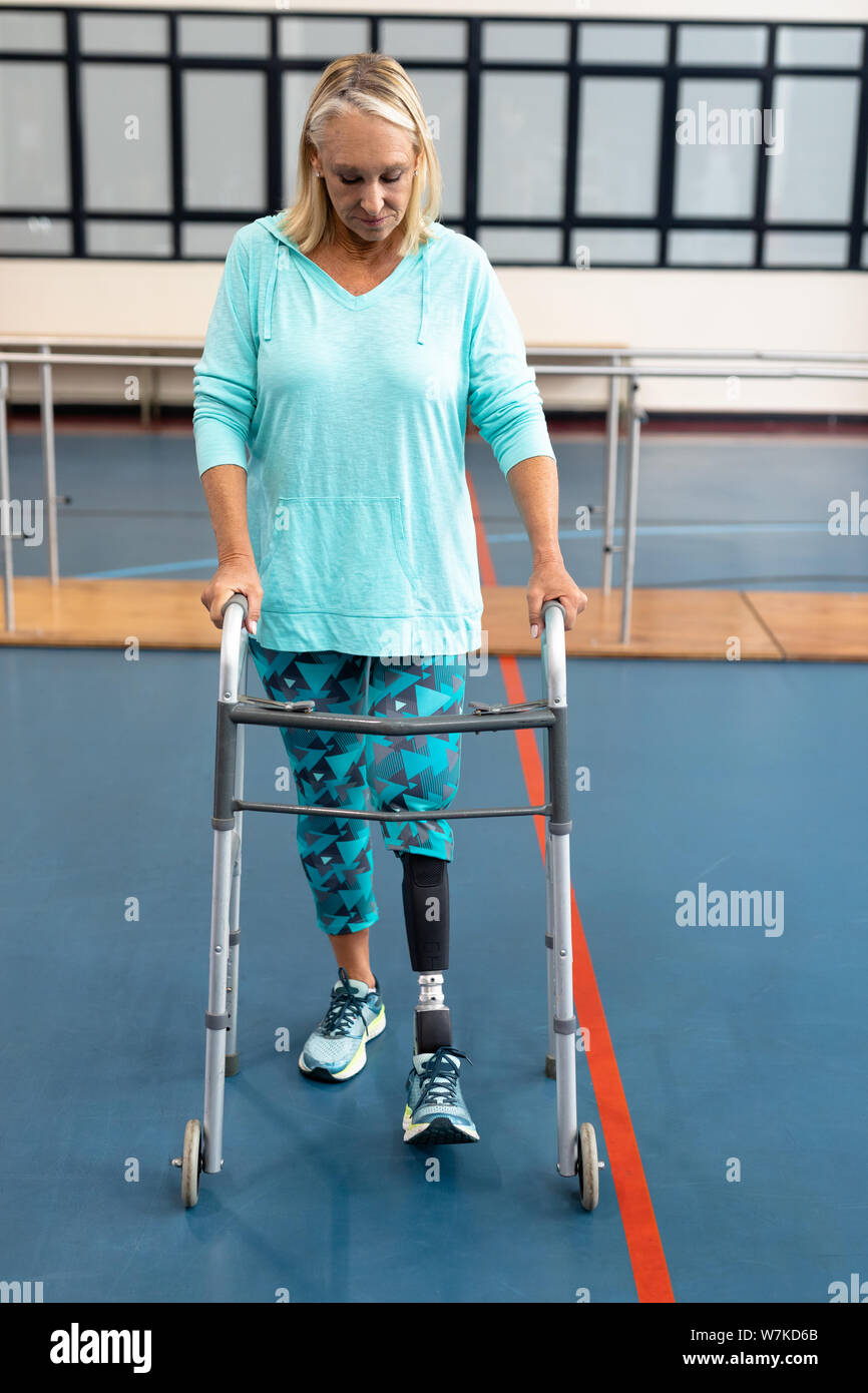 Disabled senior woman walking with walker in sports center Stock Photo ...