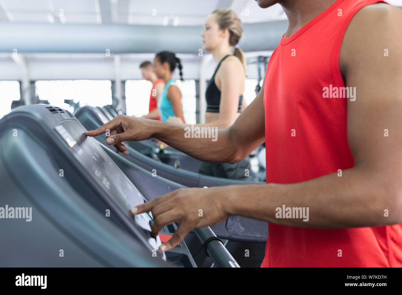 Fit man operating treadmill while exercising on treadmill in fitness ...