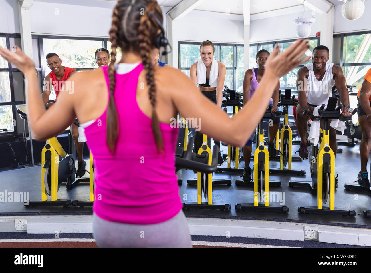Female trainer training people to work out on exercise bike Stock Photo ...