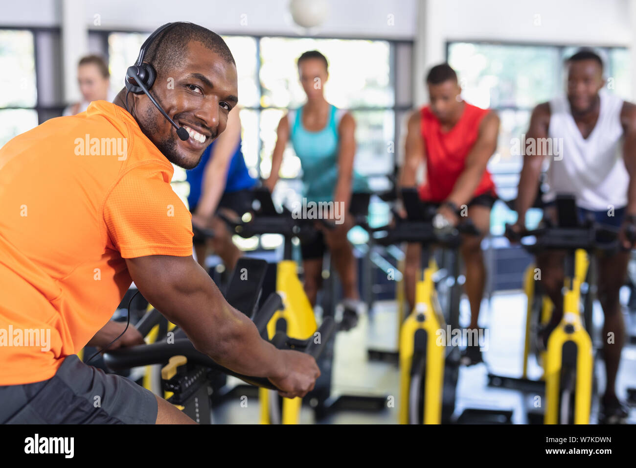 Male trainer training people to work out on exercise bike Stock Photo ...