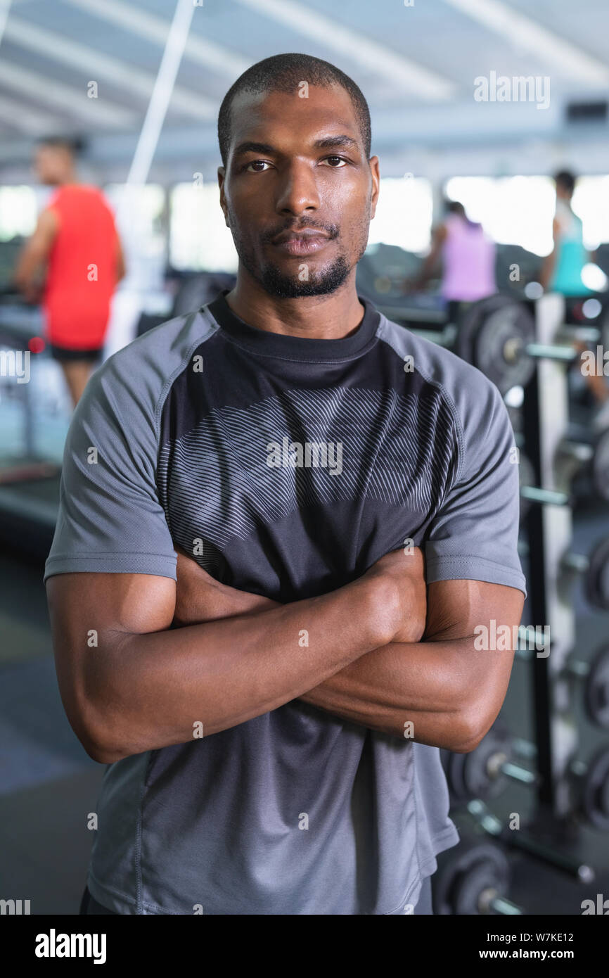 Fit man standing with arms crossed in fitness center Stock Photo - Alamy