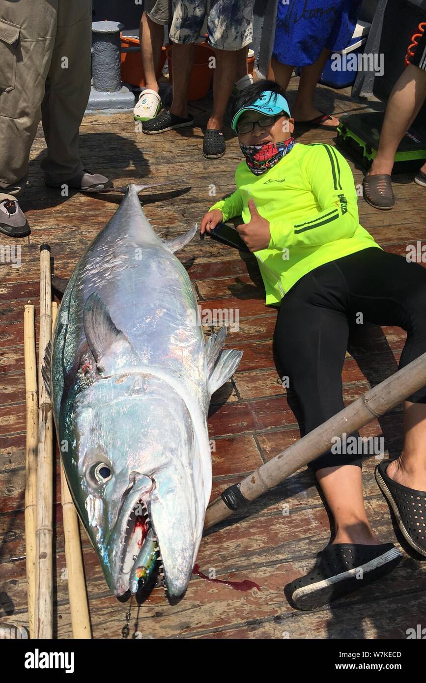 A man poses for photos with a 1.73-meter-long, 90 kilogram tuna caught ...