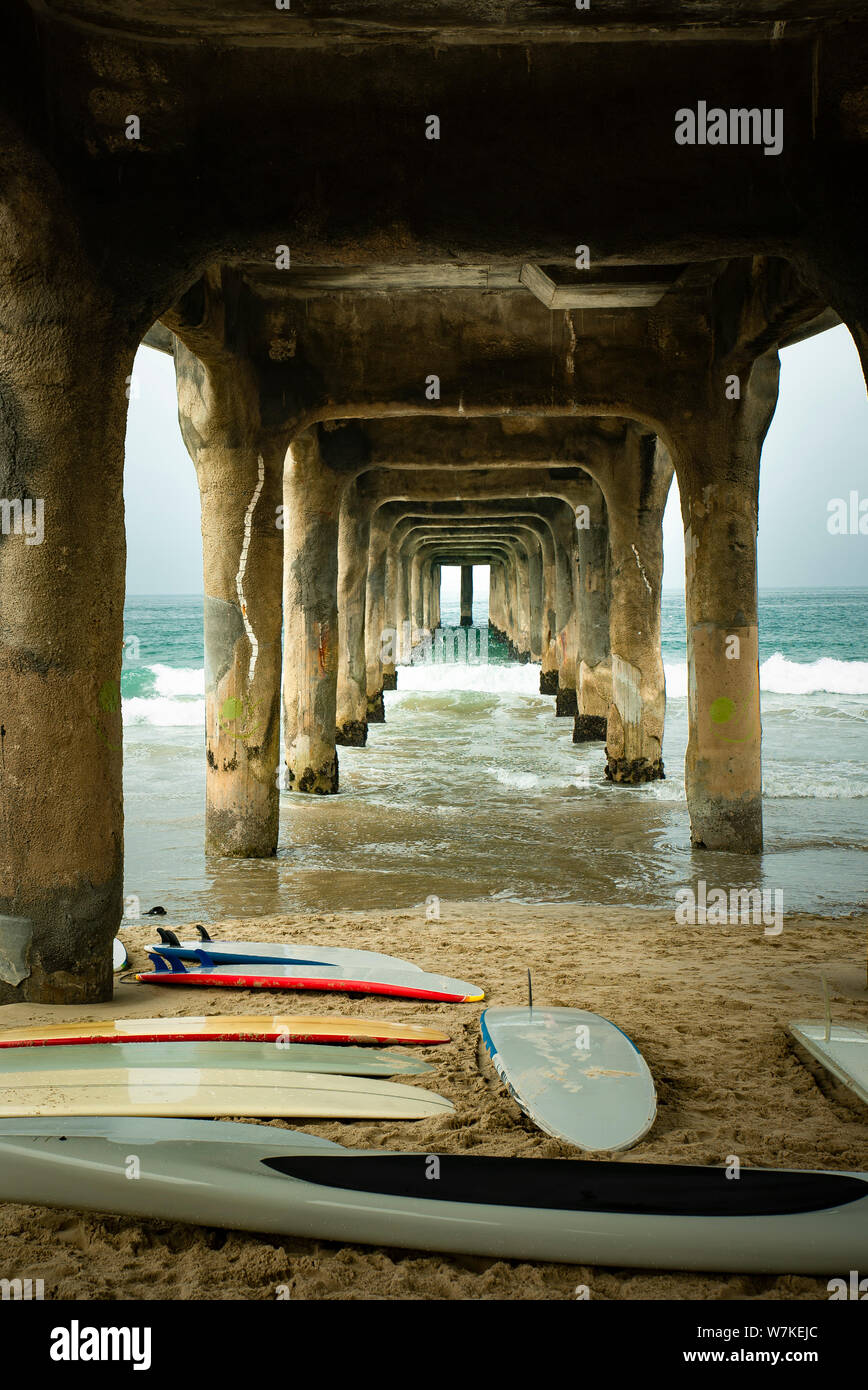 Surf boards on an empty beach under a pier Stock Photo - Alamy