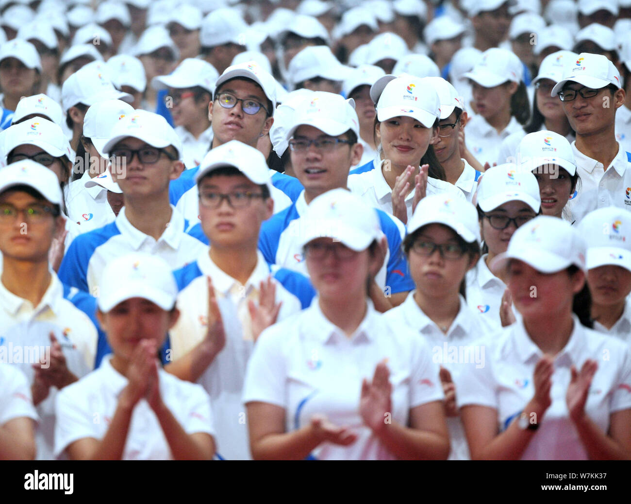 Chinese volunteers dressed in uniforms watch representatives displaying ...