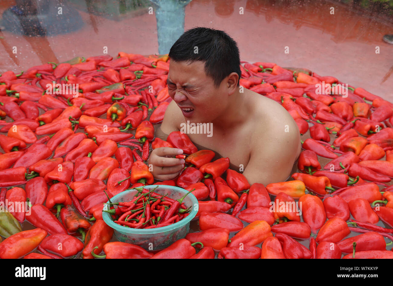 A tourist sitting in a big glass jar eats chili during an eating chili ...