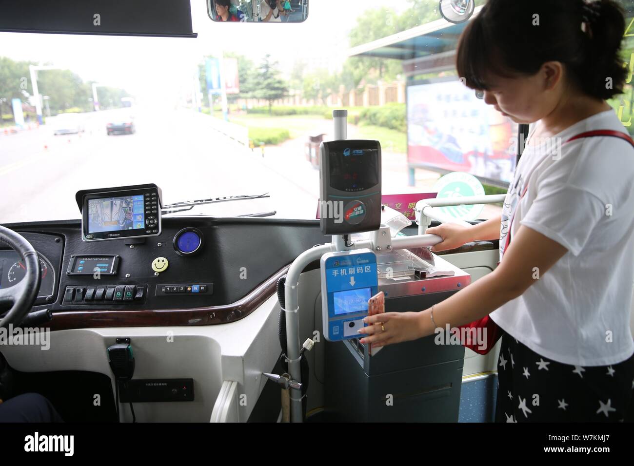 A passenger scans a QR code of the electronic bus card on her ...