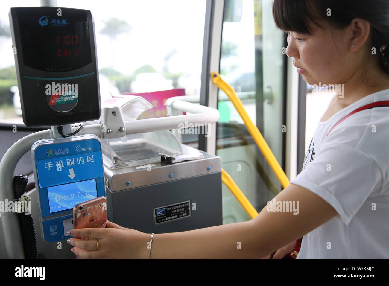 A passenger scans a QR code of the electronic bus card on her ...