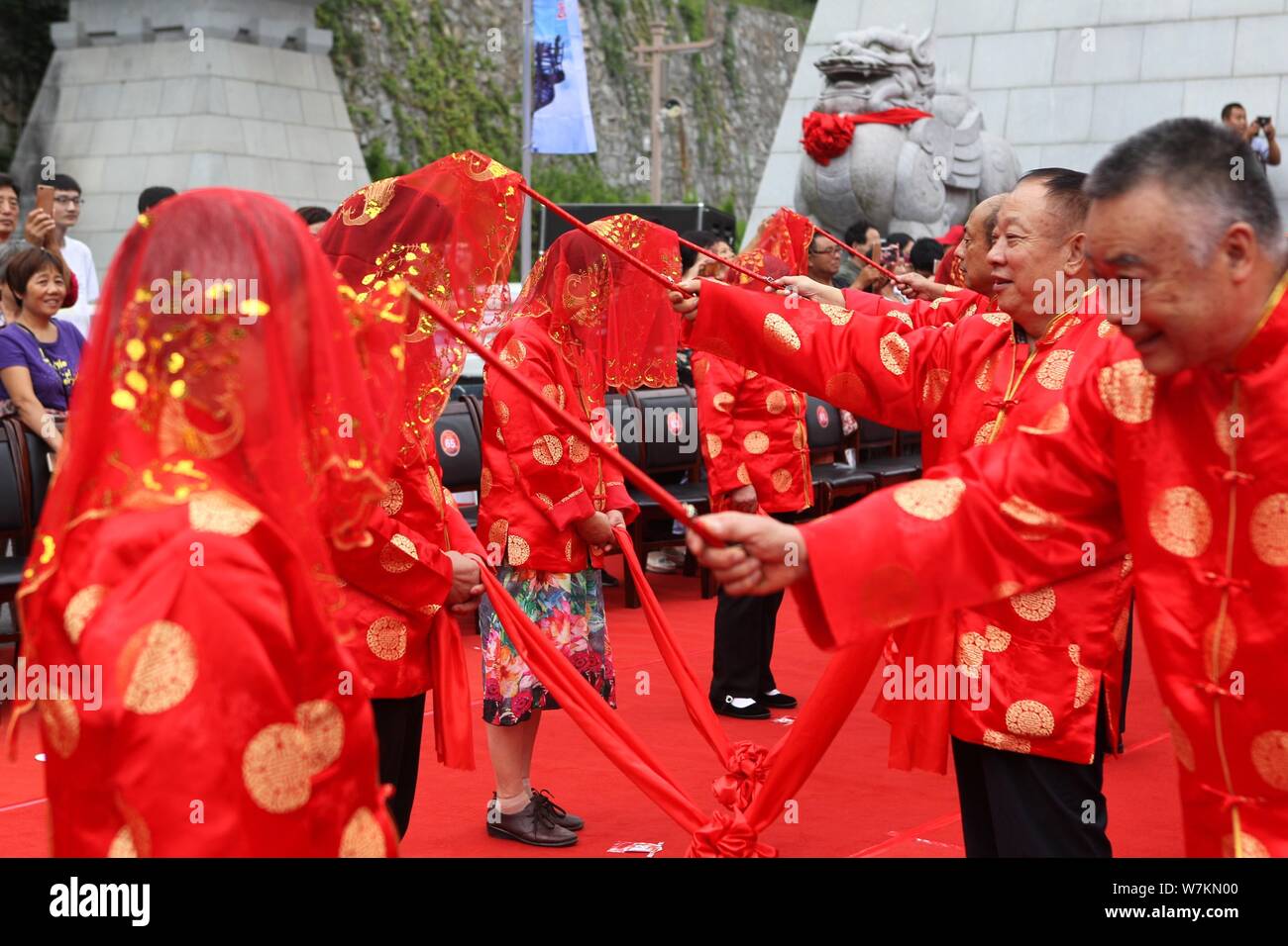 Elderly men lift the bridal veils of their wives at a ceremony event to ...