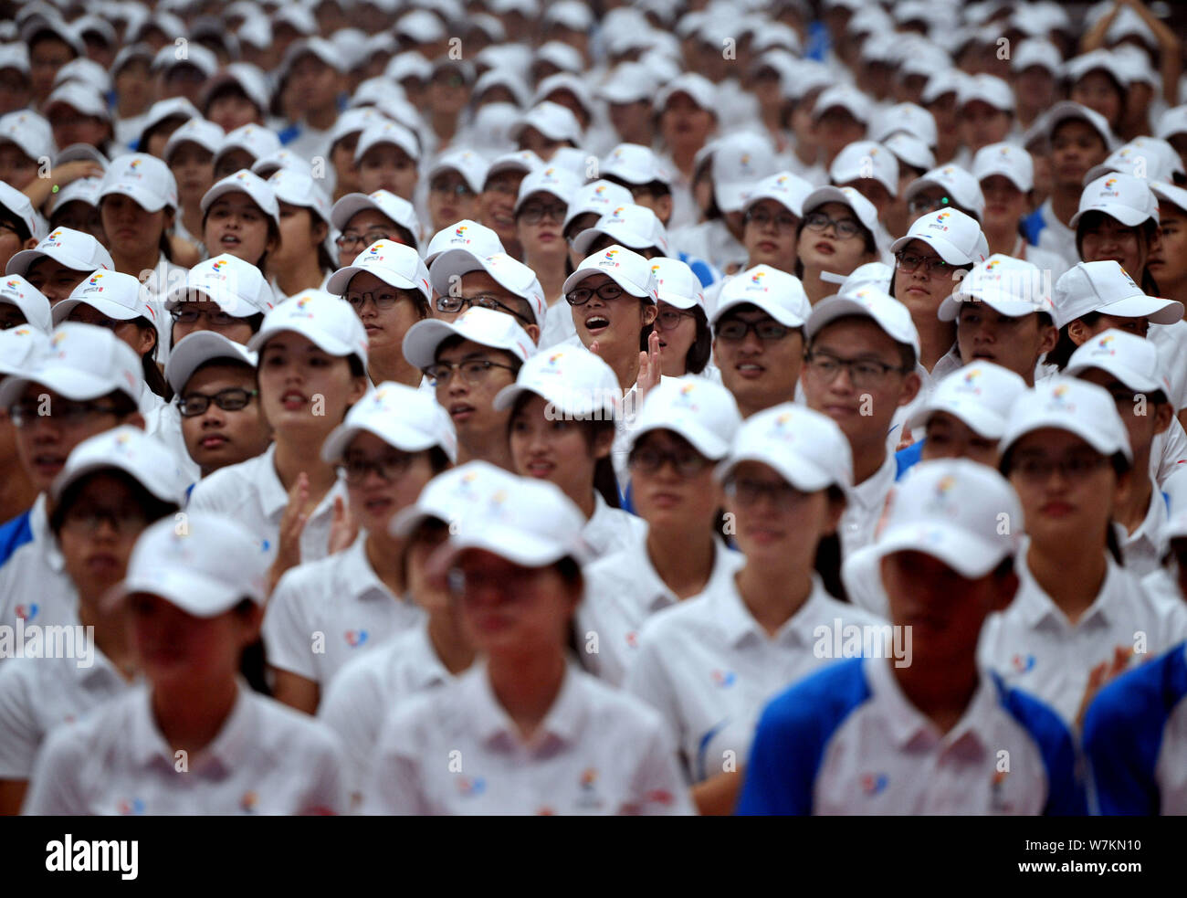Chinese volunteers dressed in uniforms watch representatives displaying ...