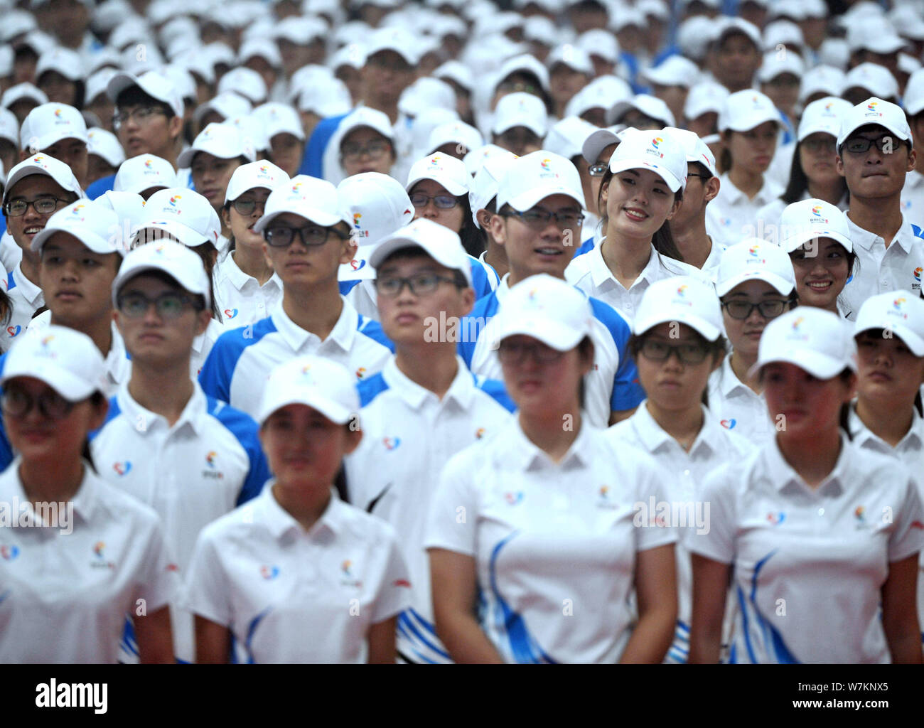 Chinese volunteers dressed in uniforms watch representatives displaying ...