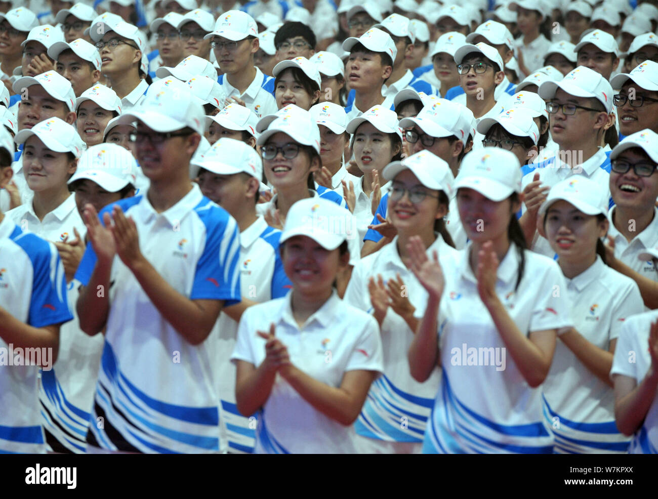 Chinese volunteers dressed in uniforms watch representatives displaying ...