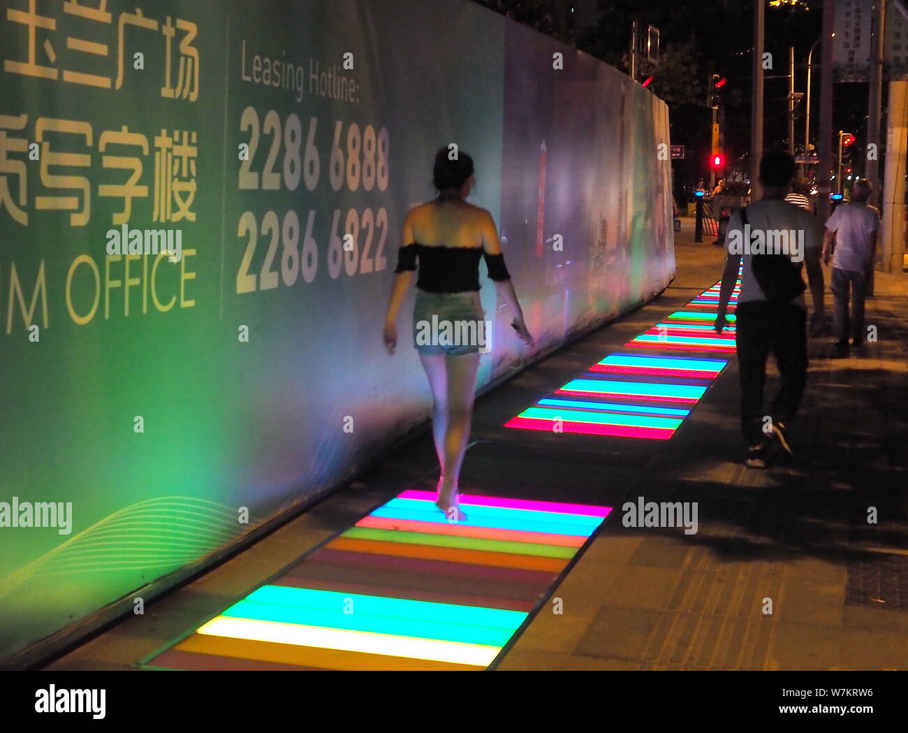 A local resident walks on the promenade featuring colourful LED lights ...