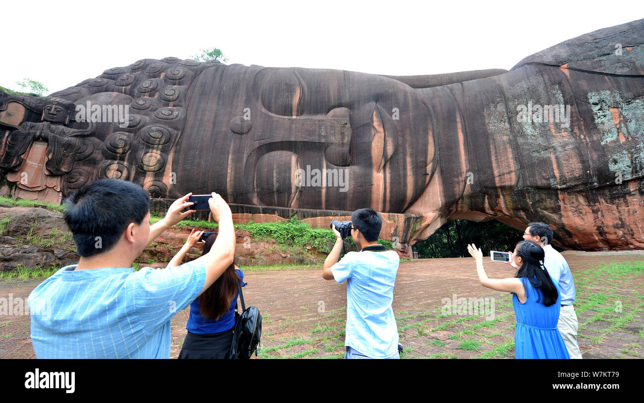 Tourists visit the world's largest reclining Buddha stone statue in Yiyang county, Shangrao city ...