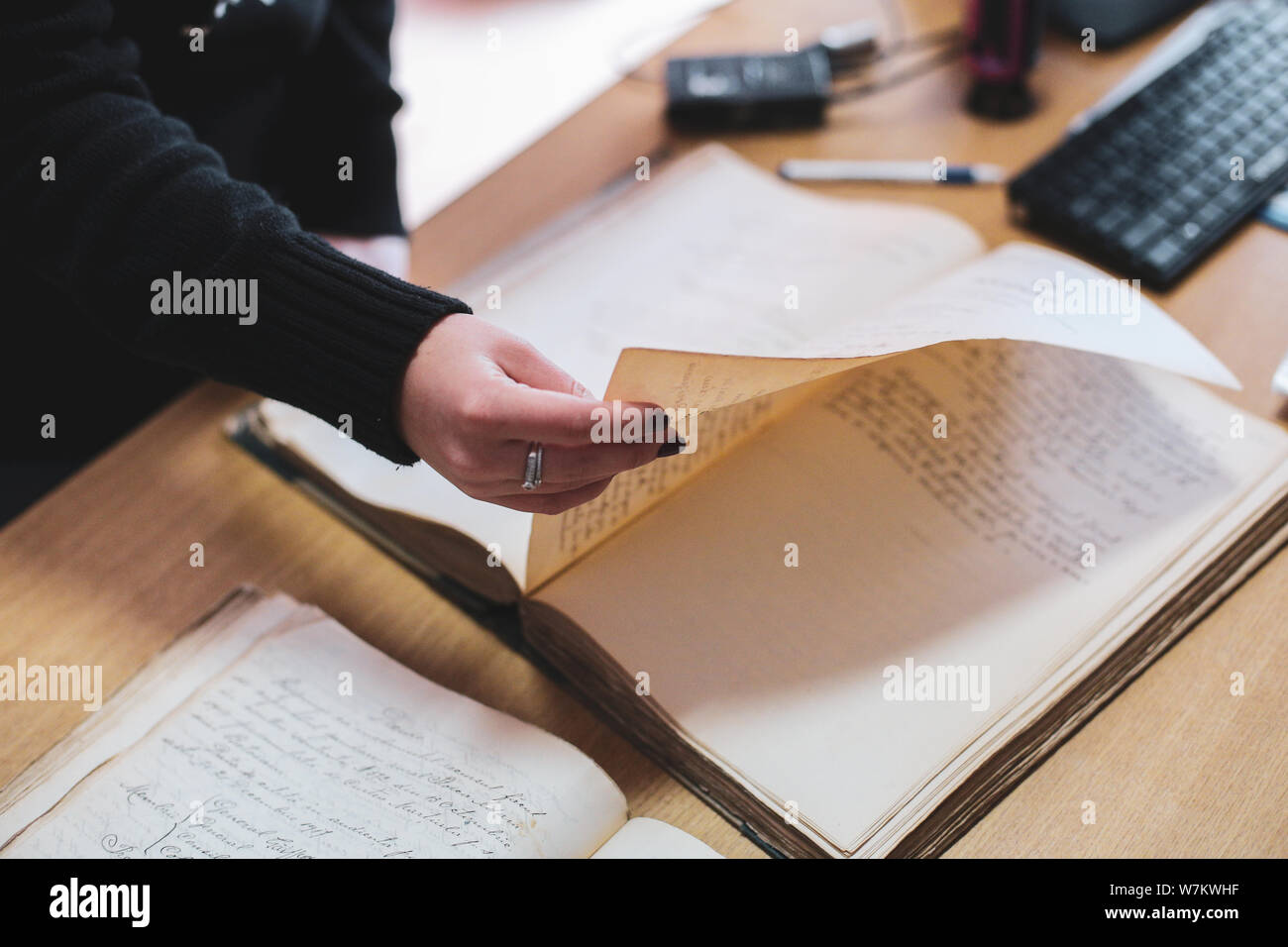 Details with the hands of a young woman reading an archive document ...