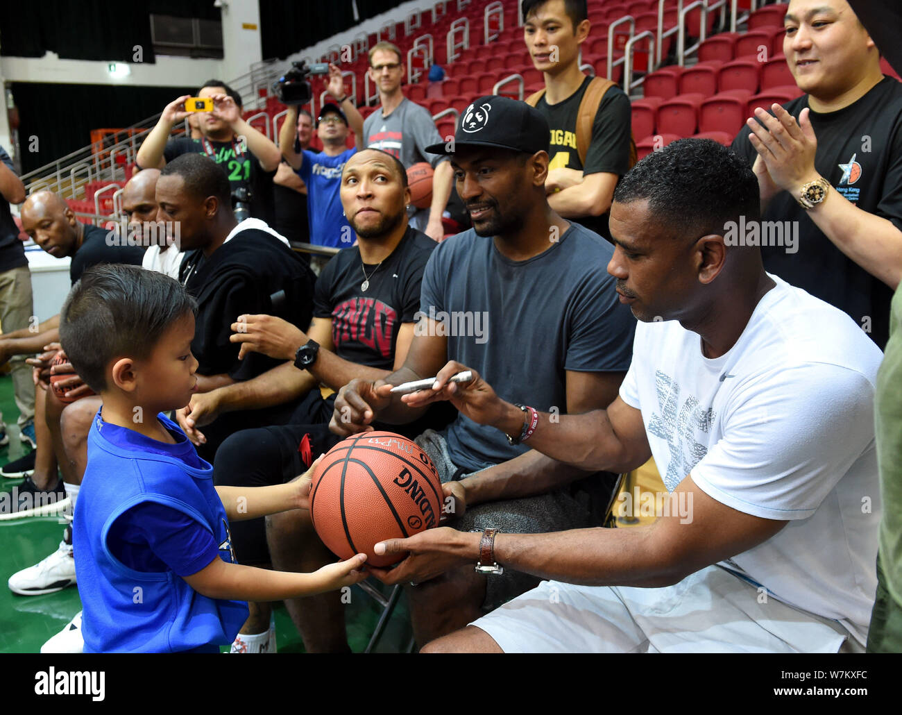 NBA star Allan Houston, right, signs for a younger player during a ...