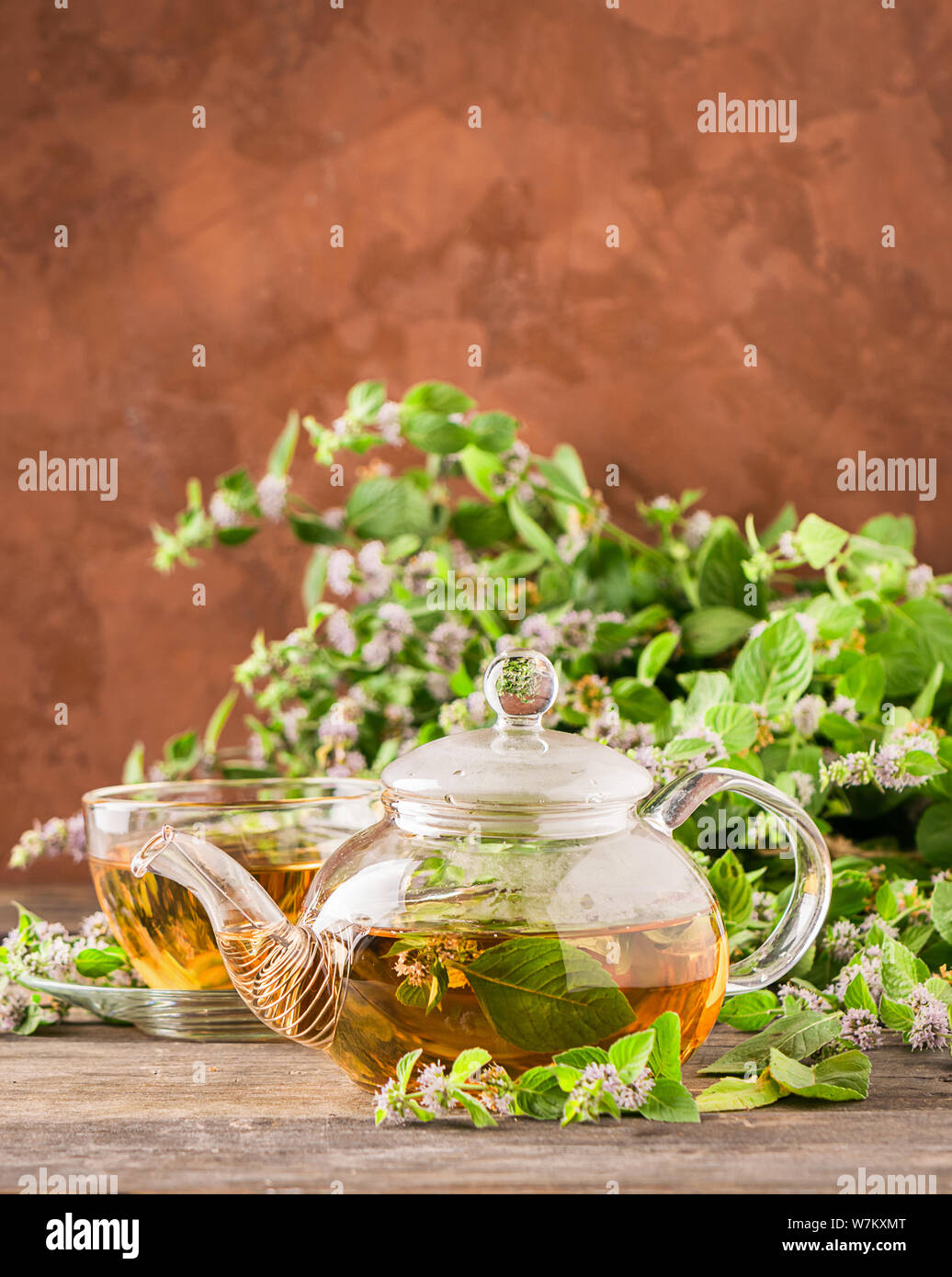 Fresh aromatic tea with melissa mint leaves glass teapot on a rustic ...
