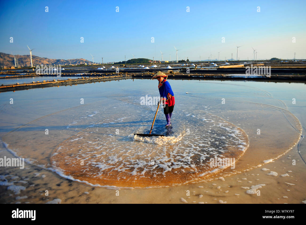 A Chinese worker collects salt during salt farming season at a ...