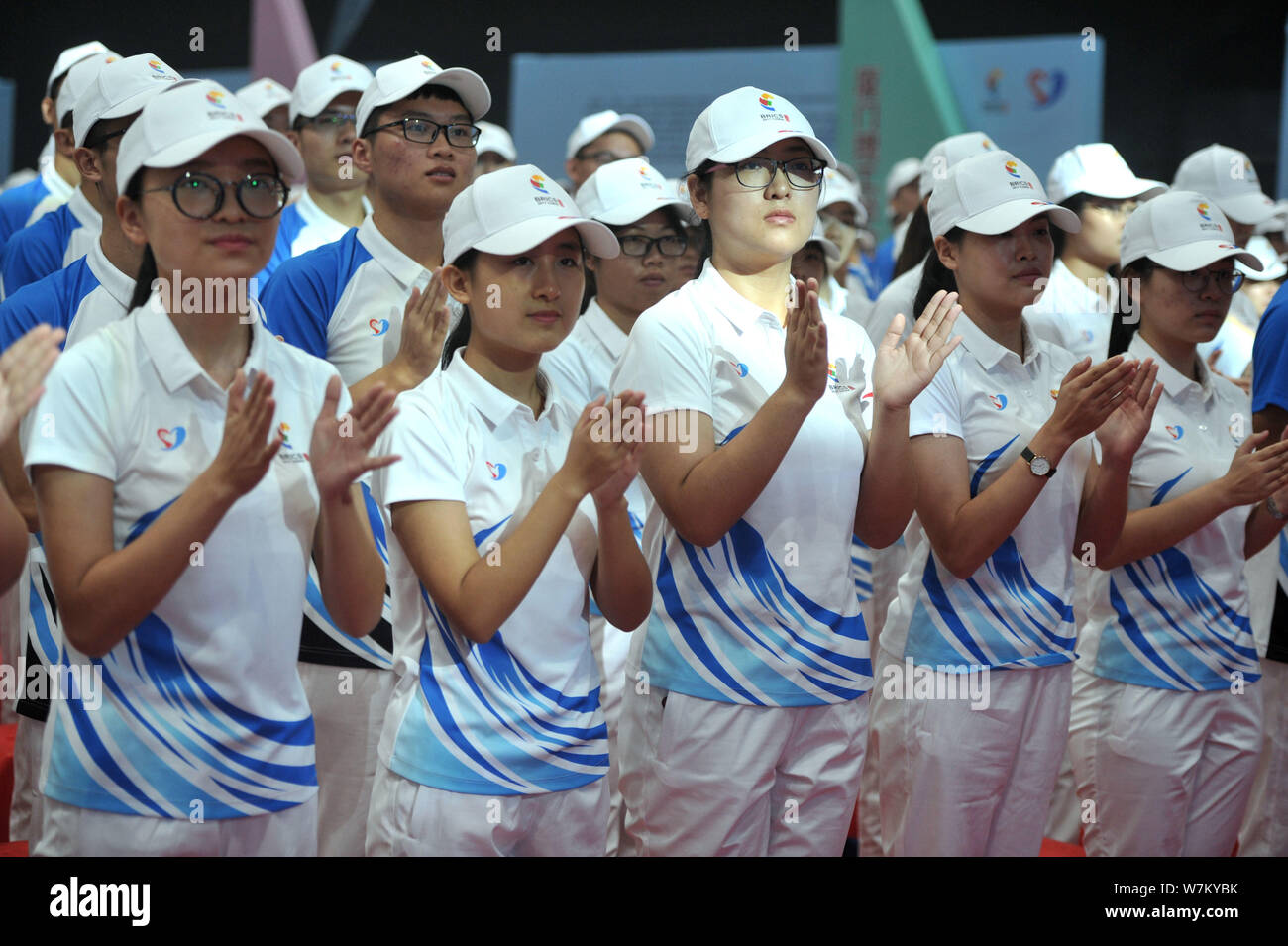 Chinese volunteers dressed in uniforms watch representatives displaying ...
