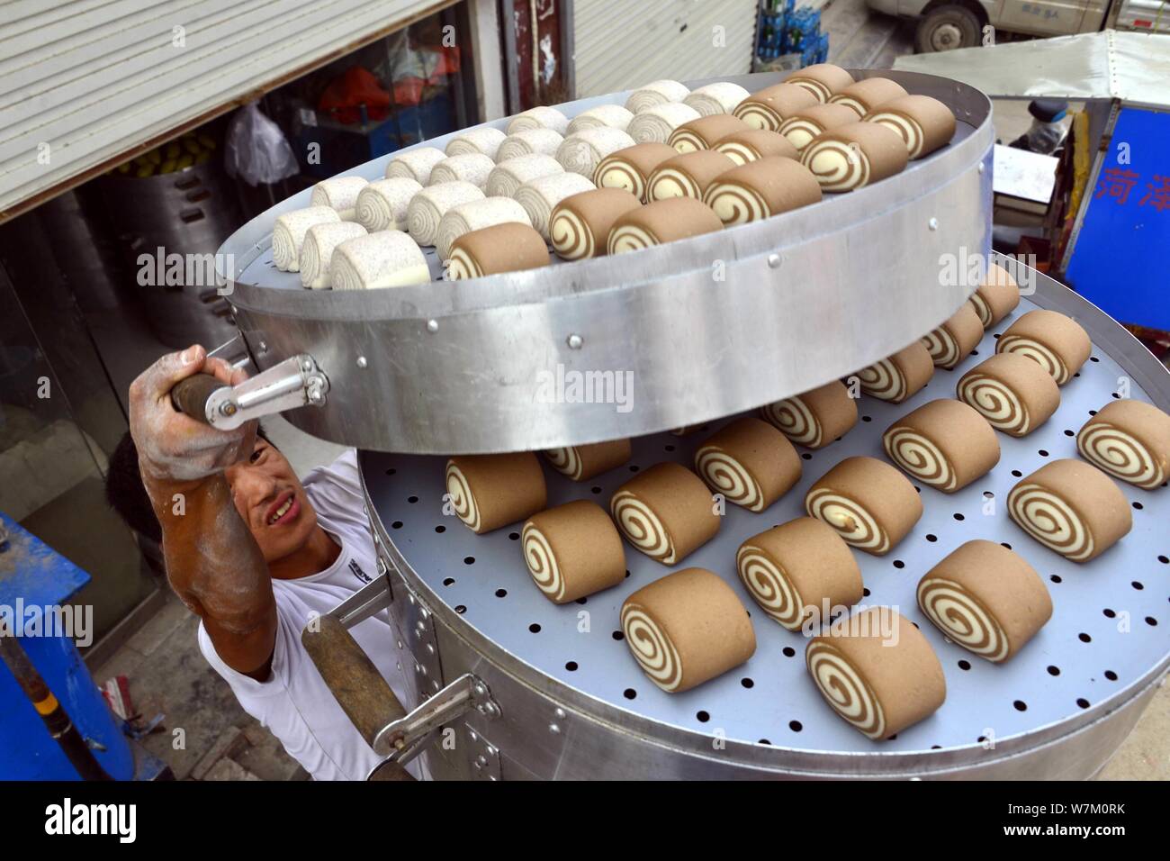 Chinese man Wang Wei moves the steamed breads, also known as mantou ...