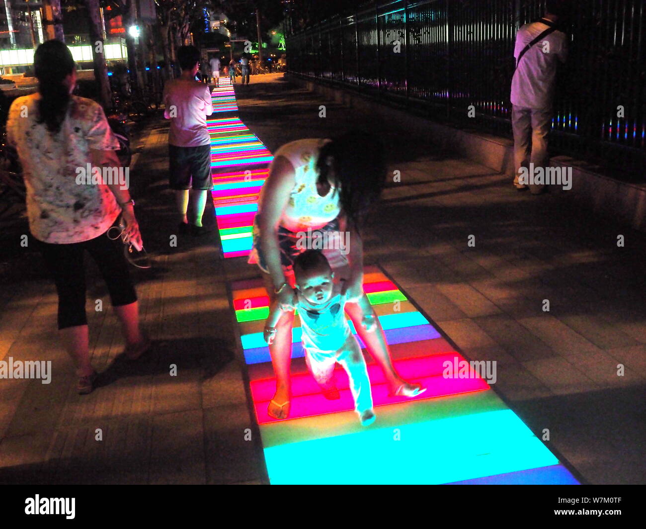 Local residents walk on the promenade featuring colourful LED lights in ...