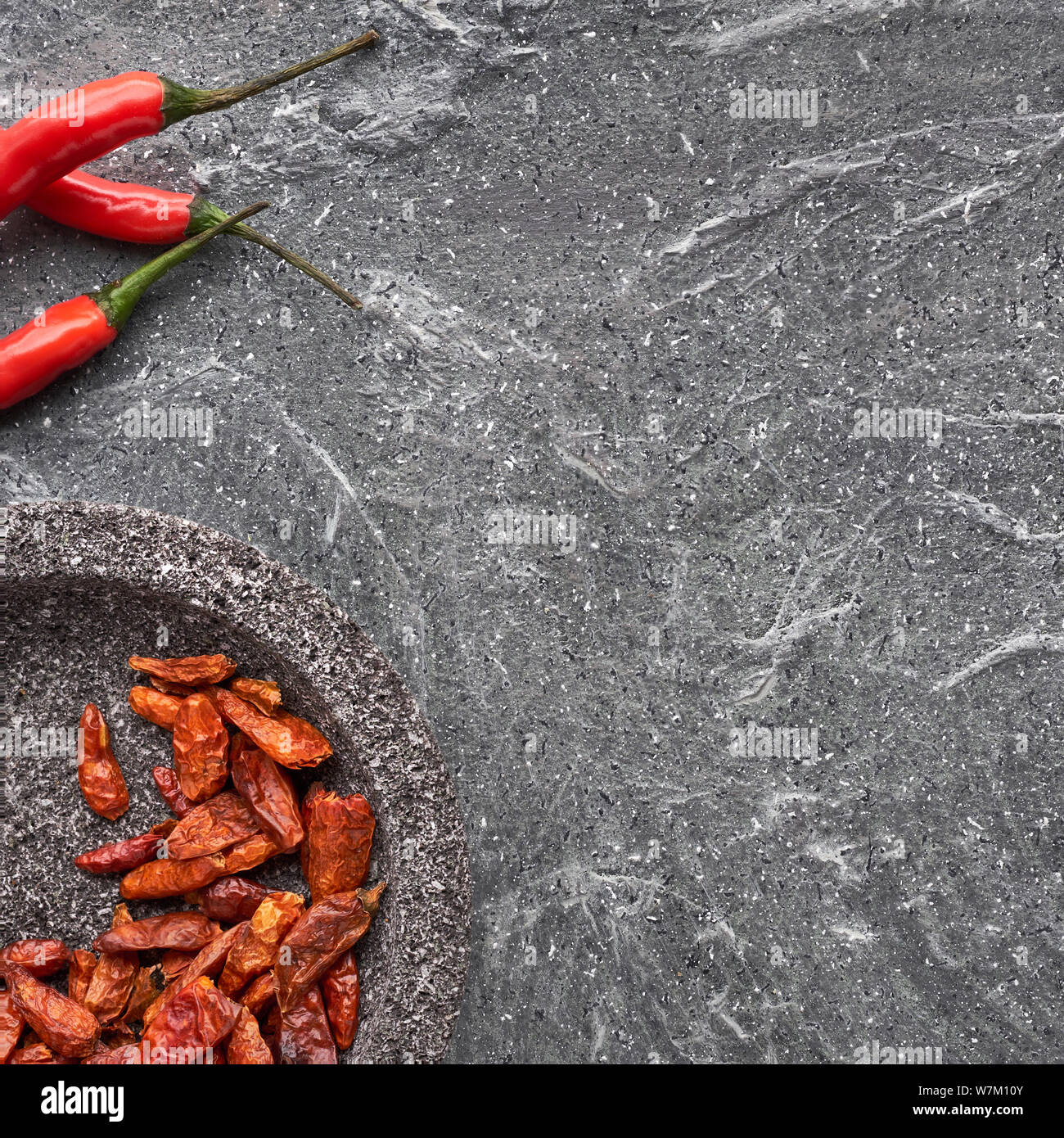 Close-up on red hot chili peppers, fresh and dry, on grey stone, top ...