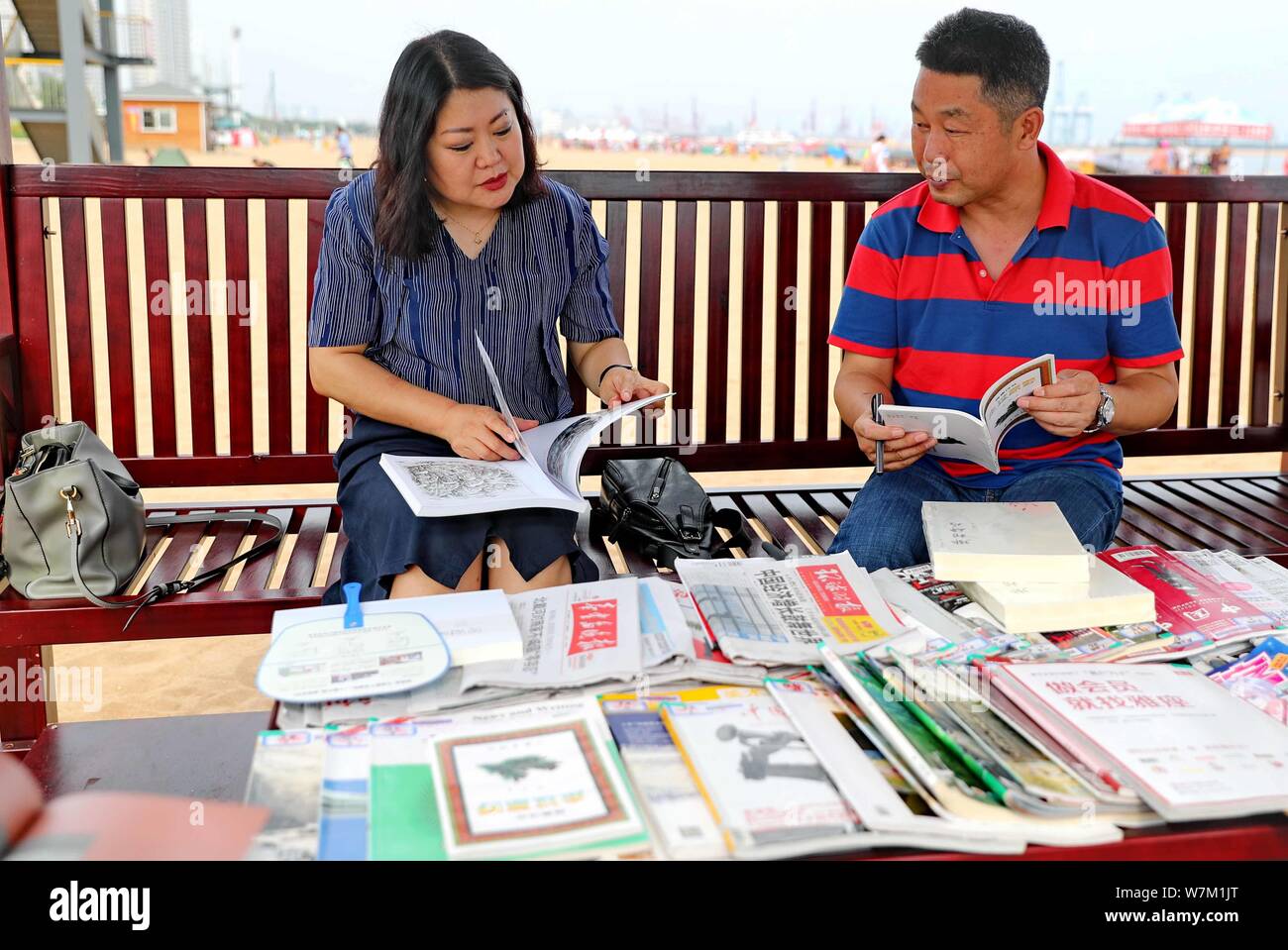 --FILE--Tourists read books at a book bar on a beach resort of Haigang ...