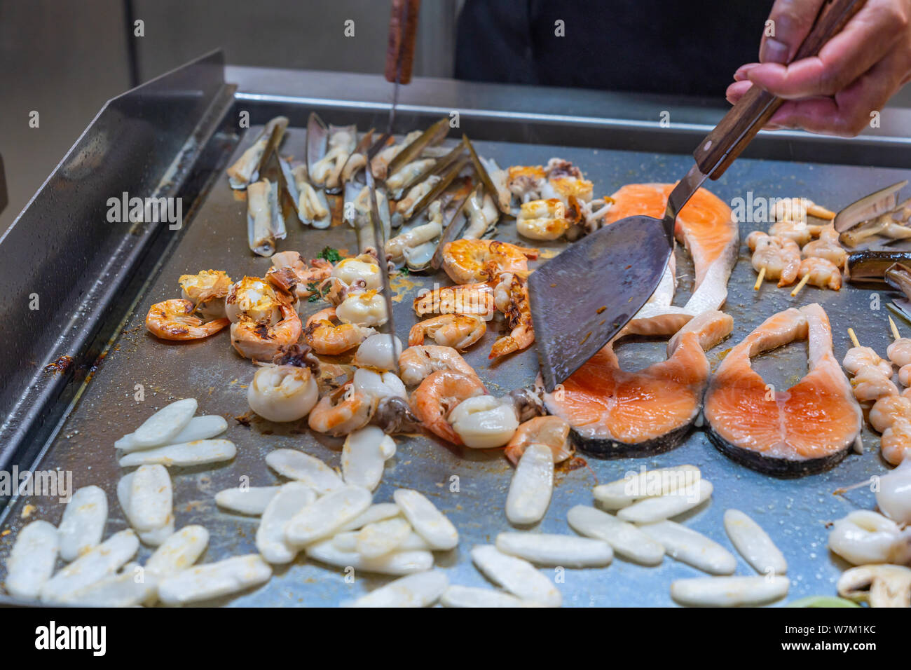 Chef using spatula frying seafood in buffet restaurant's kitchen Stock ...