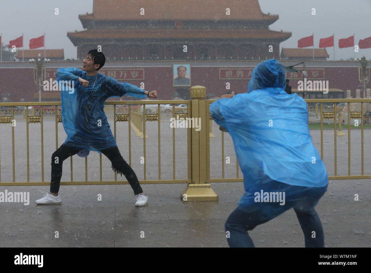 A tourist in rain coat poses for a photo in heavy rain on Tian'anmen ...