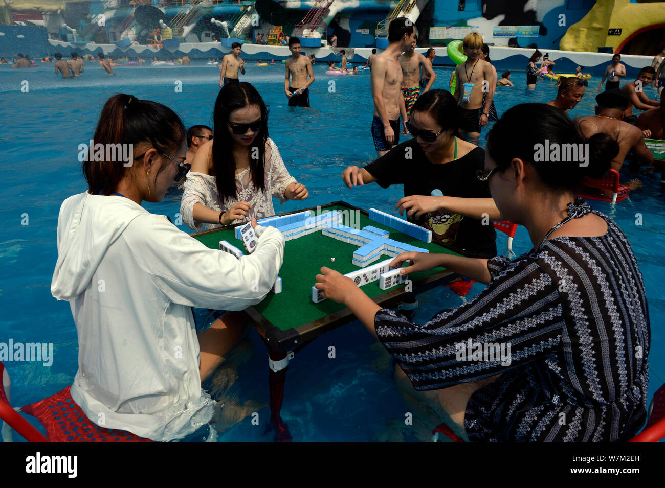 Chinese holidaymakers play mahjong in the water at a water park in ...