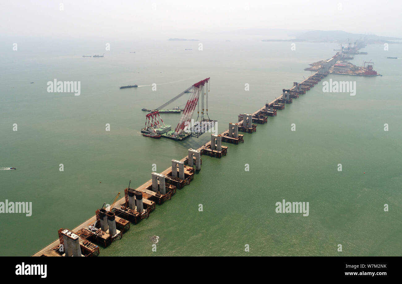 A crane ship lifts the first steel truss girder to the bridge piers of ...