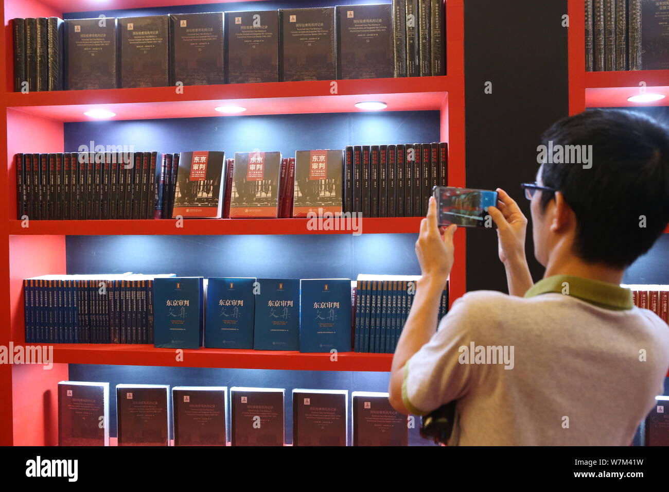 A visitor takes photos of books of Collected Works of the Tokyo Trial ...