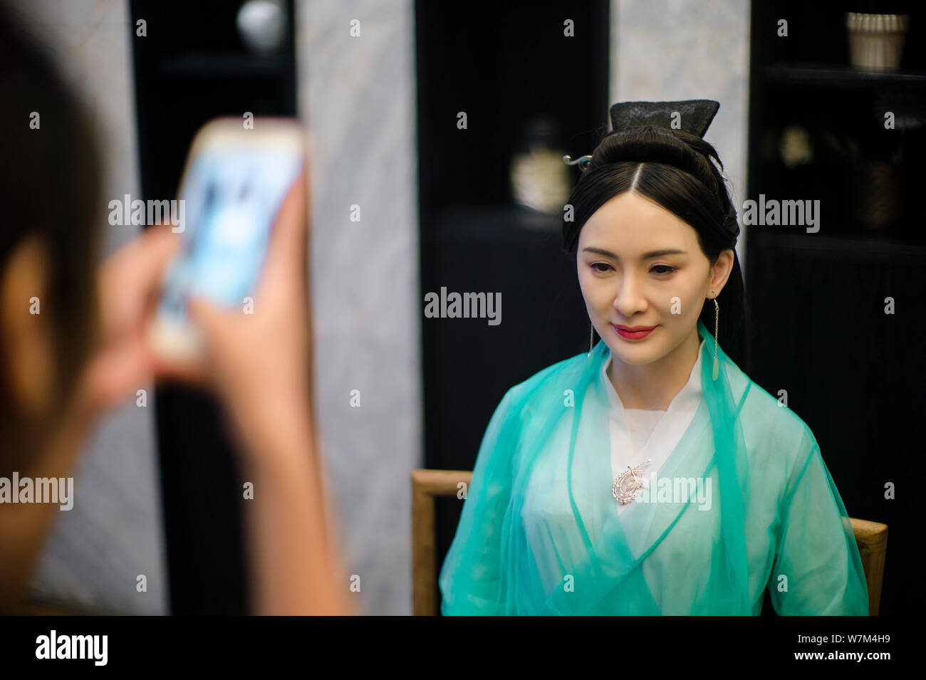 A customer takes photos of a wax figure of Chinese actress Yang Mi ...